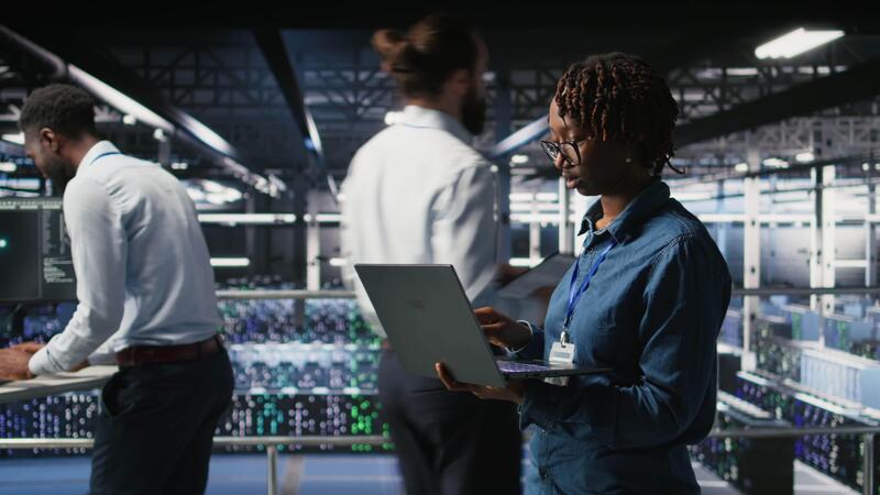 System Administrators On Data Center Industrial Platform Analyzing Performance Outputs On Laptop