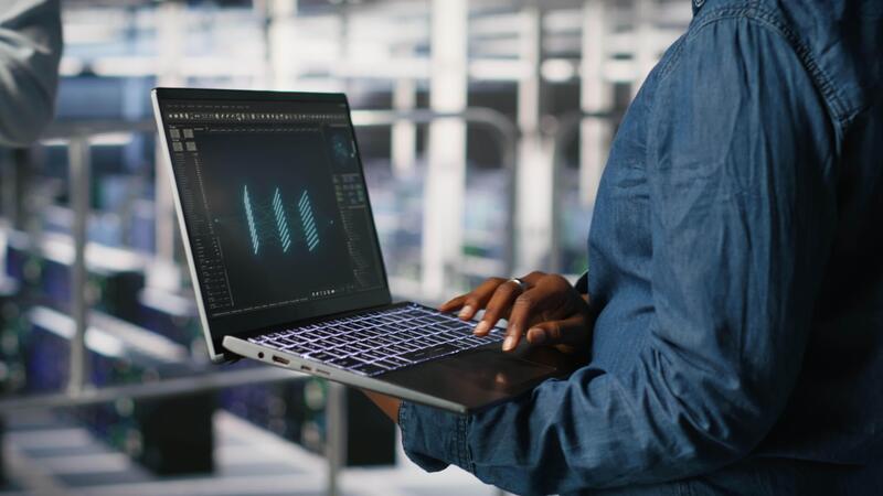 Close up of admin in data center using laptop to monitor neural network LLM visualization ...