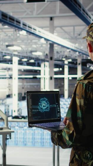 Vertical Army programmer in high tech server hub uses AI application on laptop to review ...