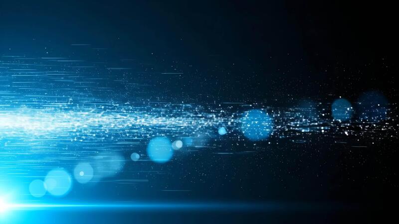 Abstract blue light streaks and particles on a dark background create a ...